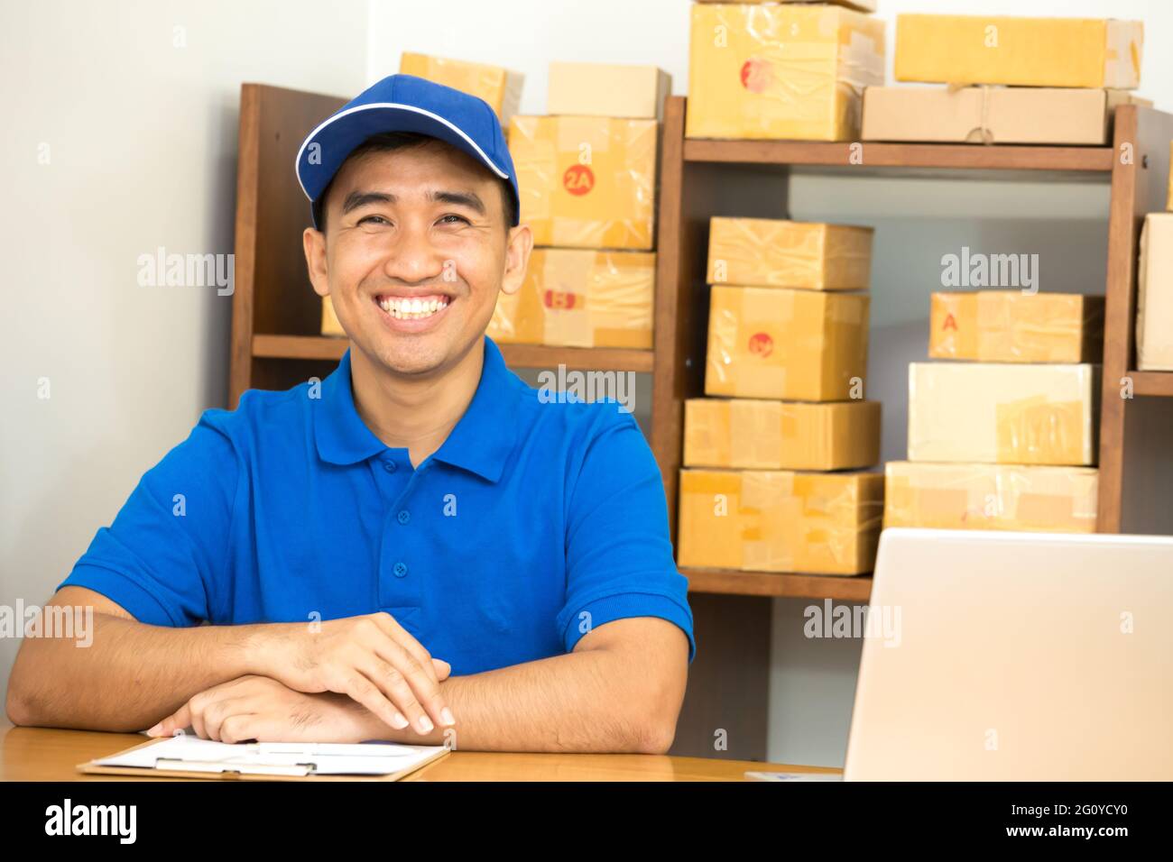 Courier man sitting and smiling with box delivery package at post ...