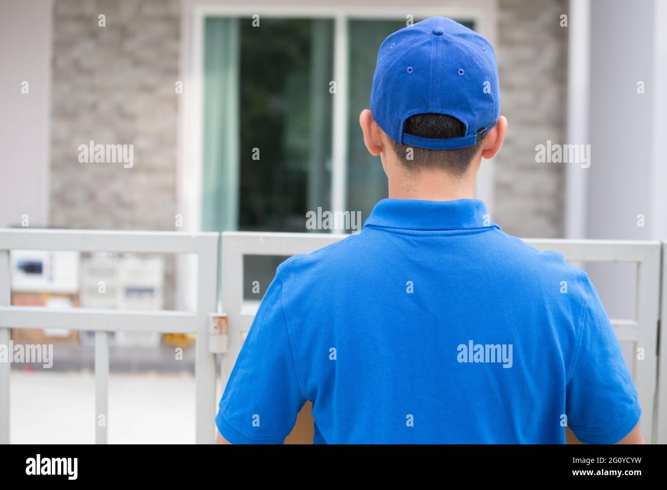 Back view of delivery man holding parcel box standing in front of the ...