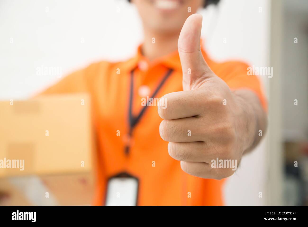 Deliveryman giving thumbs up and carrying a parcel box Stock Photo - Alamy