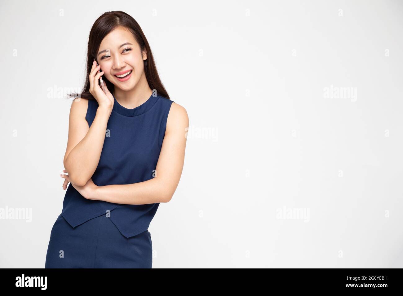 Asian woman smiling while talking on the phone isolated on white ...