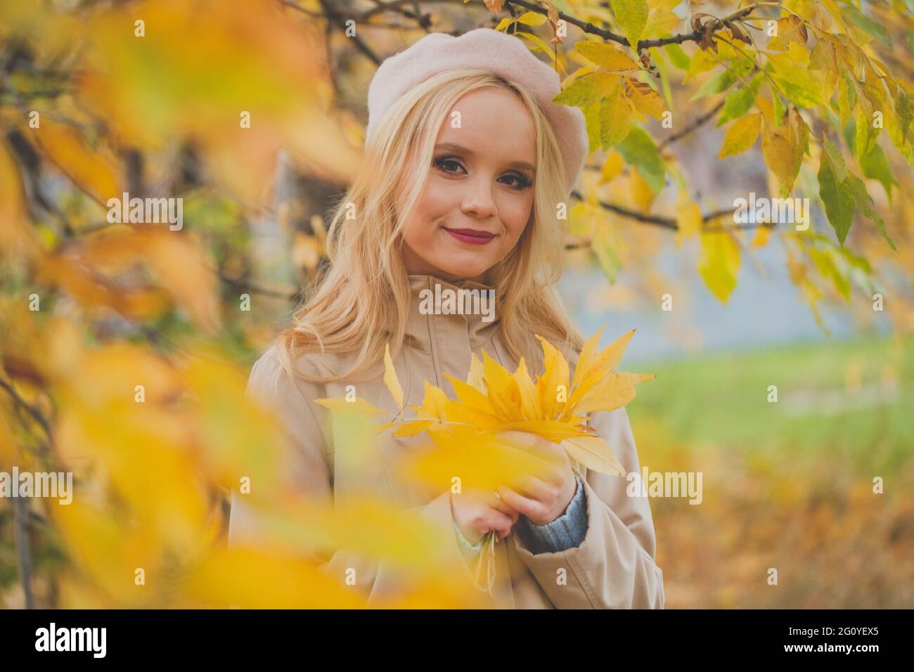 Happy smiling woman holding in her hands yellow leaves in fall park ...