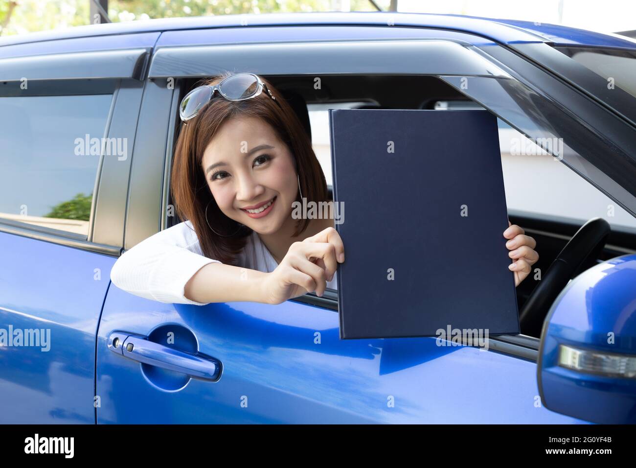 Happy Asian woman holding car insurance document book and sitting in ...