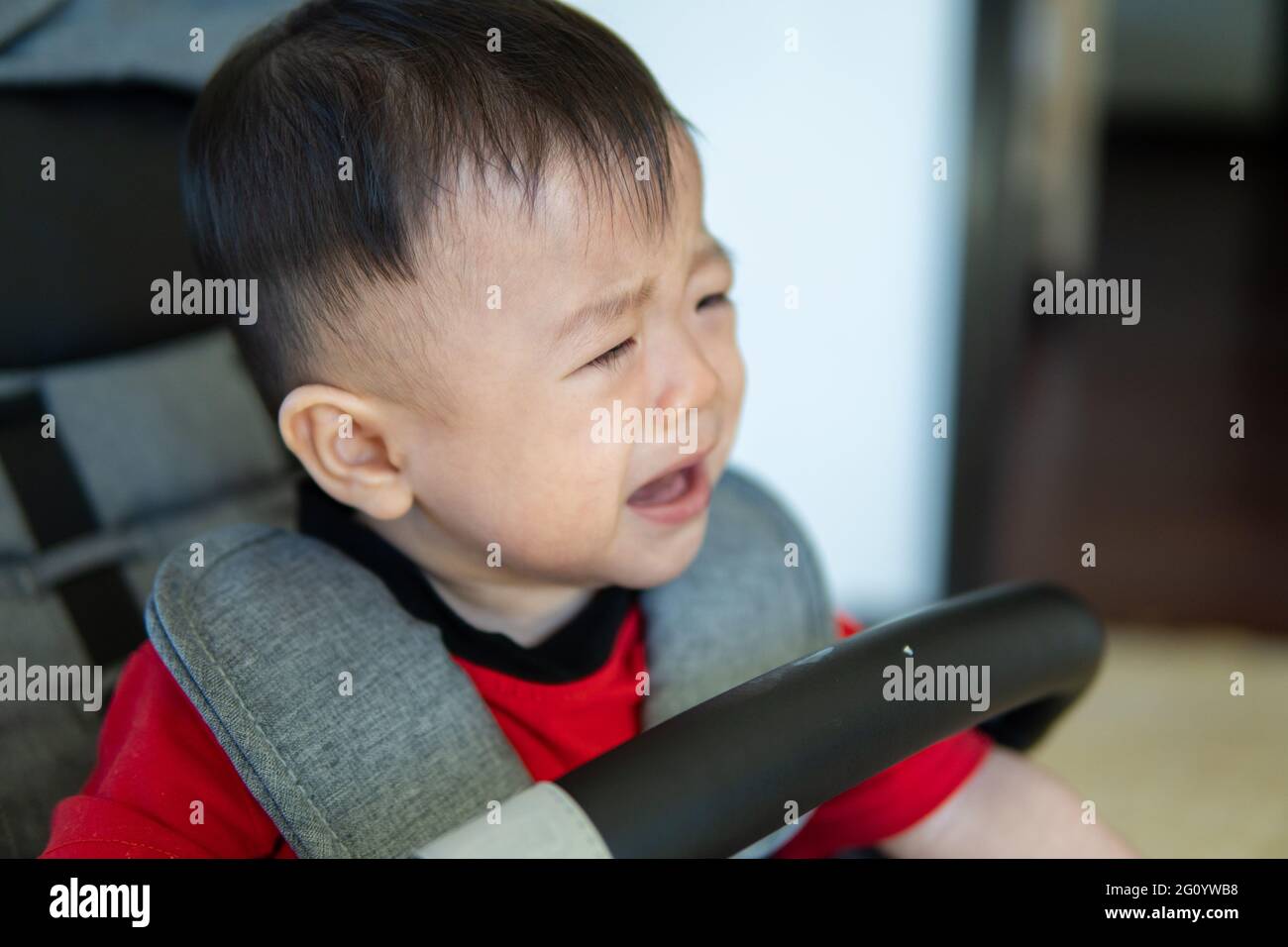 Cute Asian Chinese baby boy sitting on stroller and crying during short ...