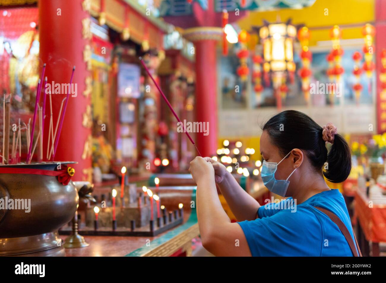 Chinese Lady with medical face mask pray with holding smoking incense ...