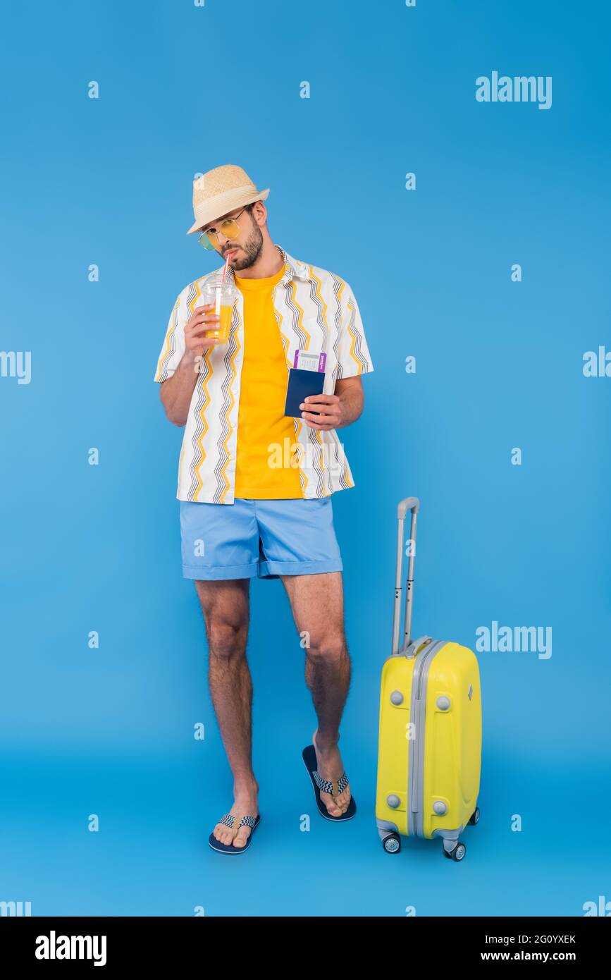 Man in sunglasses drinking orange juice and holding passport near ...