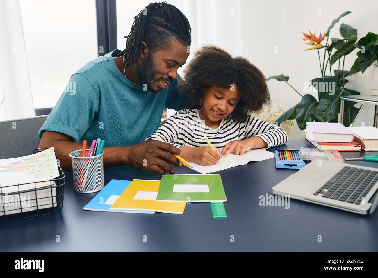Father helps his daughter doing school homework at home. Father's day ...