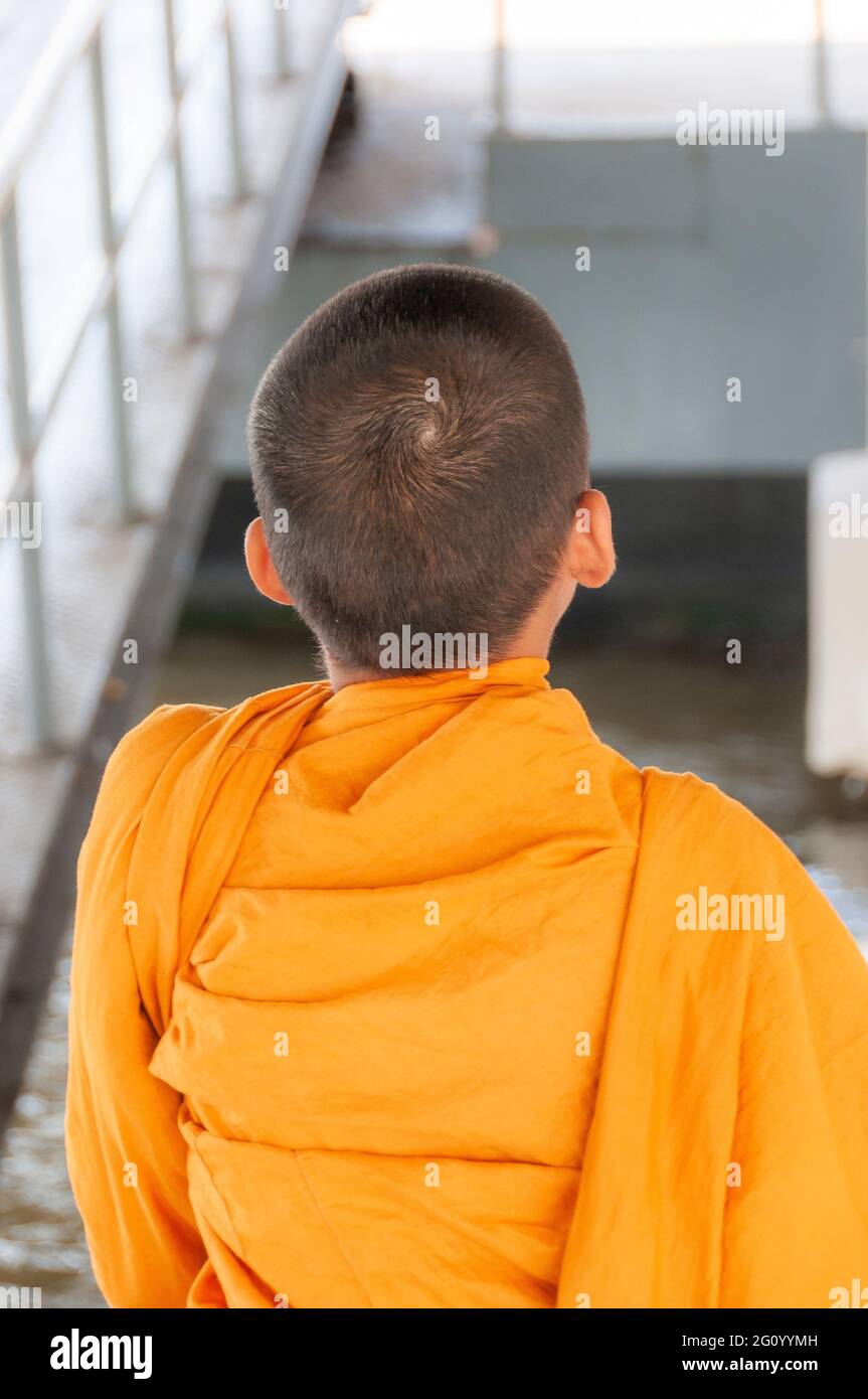 The rear view of a young Buddhist Monk wearing saffron robes in Bangkok ...