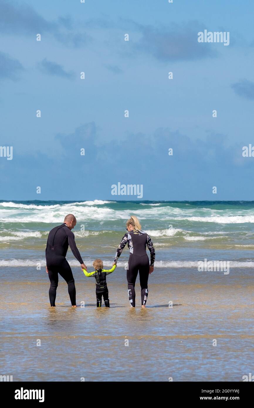 A mother and father holding hands with their toddler child paddling in ...