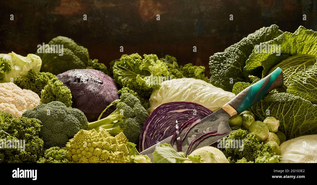 Pile of assorted types of cabbages placed on counter with knife at ...