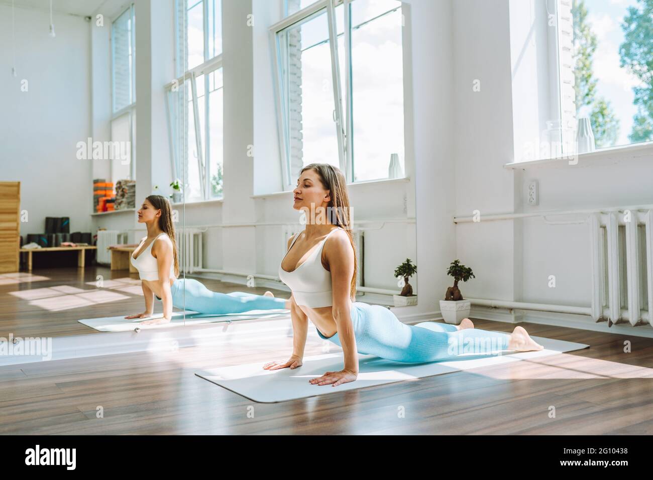 Young female do complex of stretching yoga exercises on floor in light ...