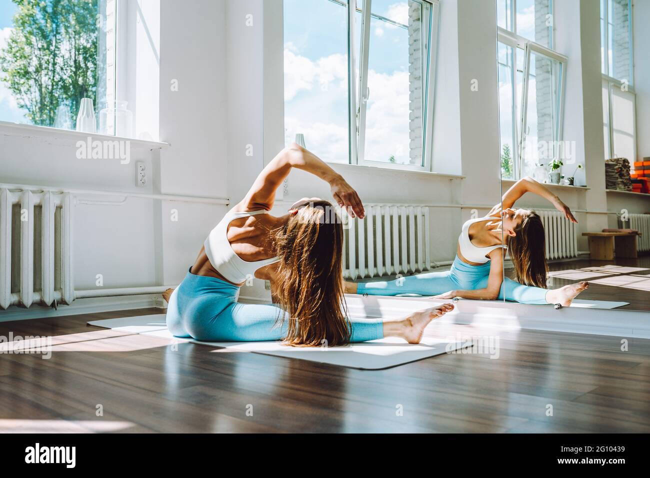 Young female do complex of stretching yoga exercises on floor in light ...