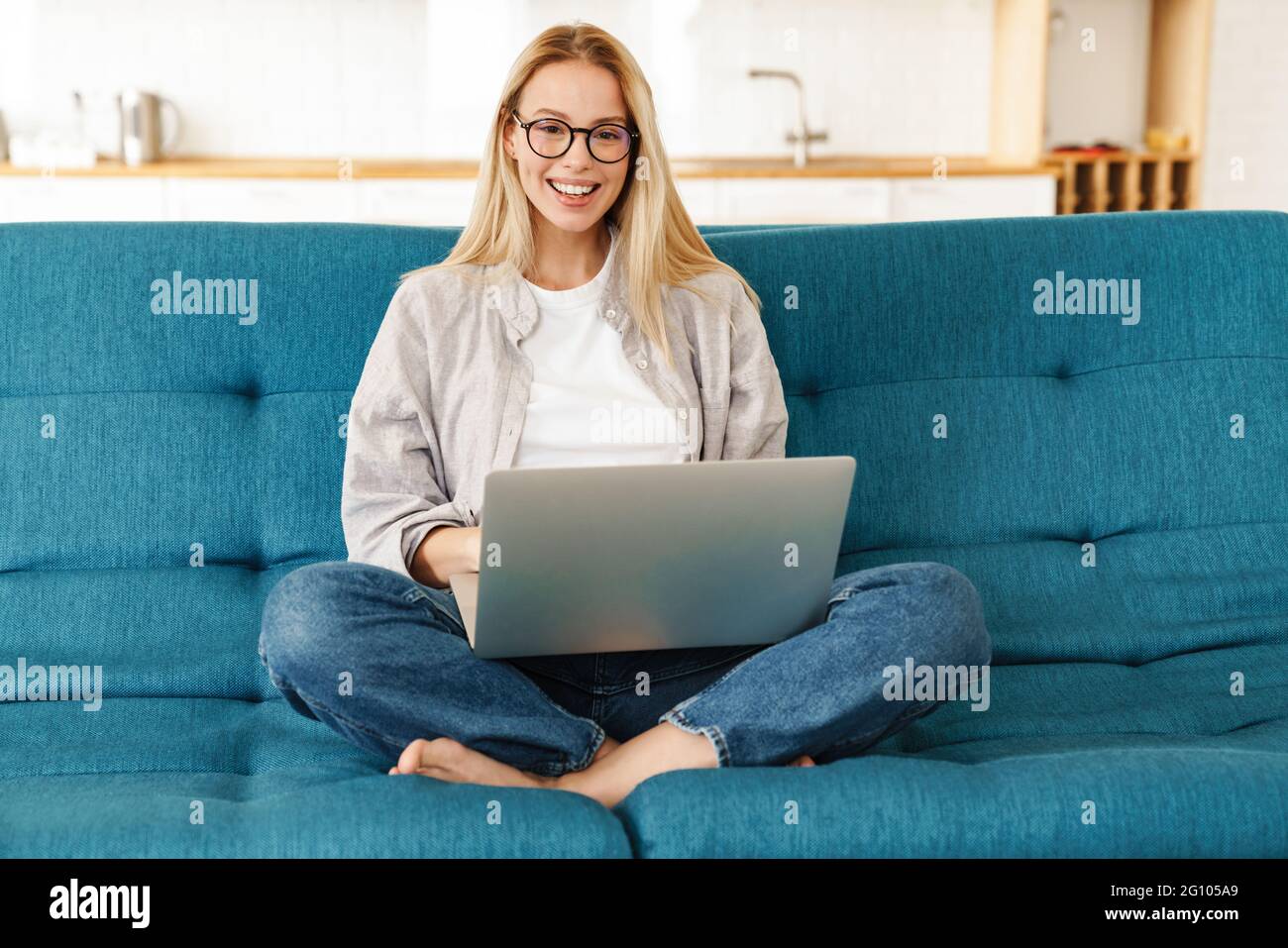 Attractive young smiling woman using laptop computer while sitting on a ...