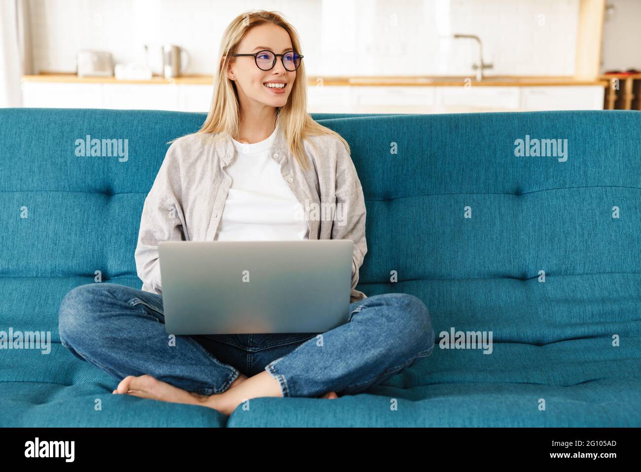 Attractive young smiling woman using laptop computer while sitting on a ...