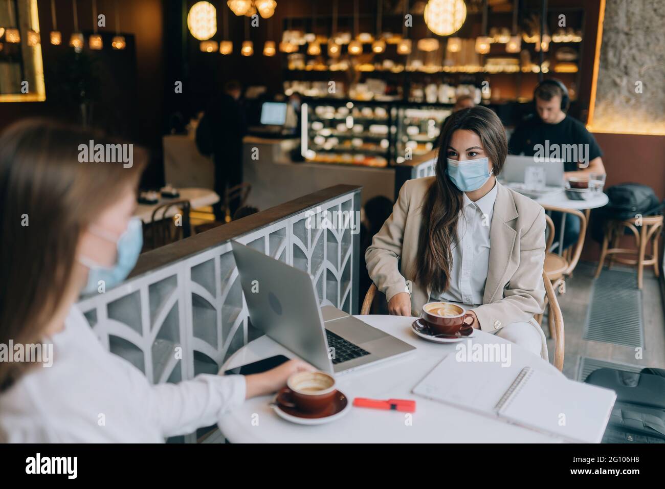 Two pretty women wearing medical face mask, using laptop to work Stock ...
