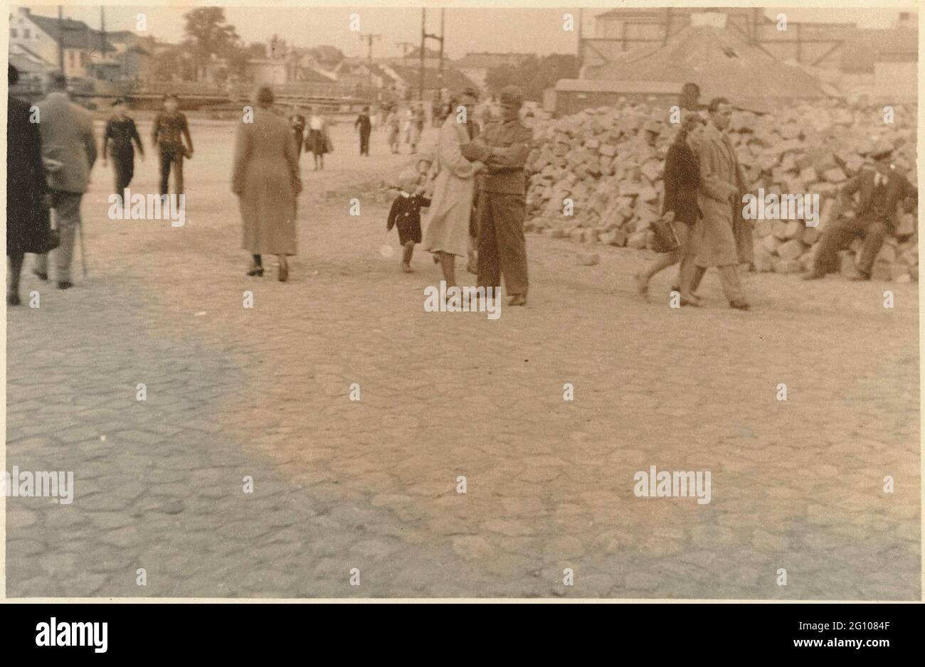 A ruined house. Citizens and soldiers walk on the street along a ruined ...