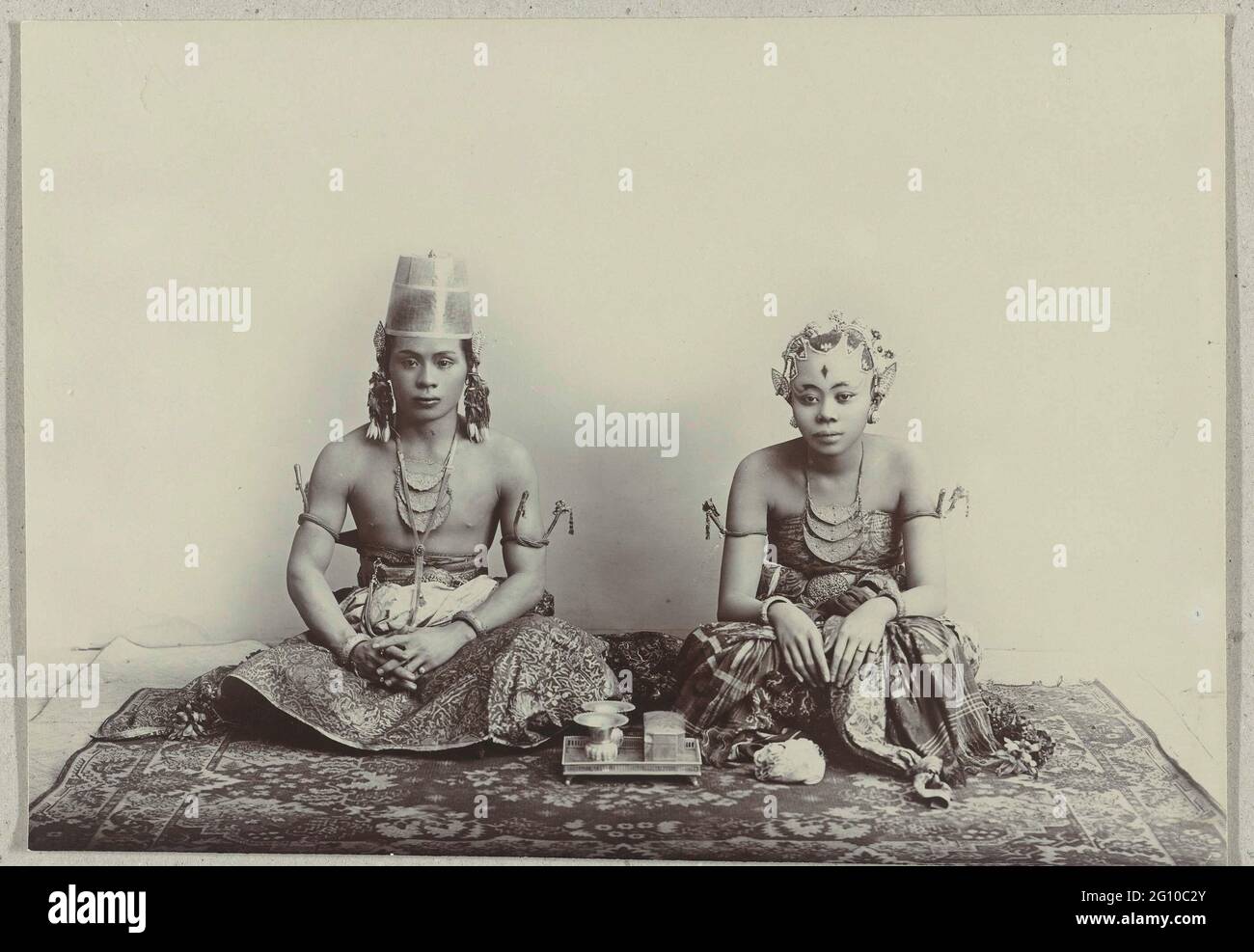 Studio portrait of a sitting young Javanese man and woman wearing a ...