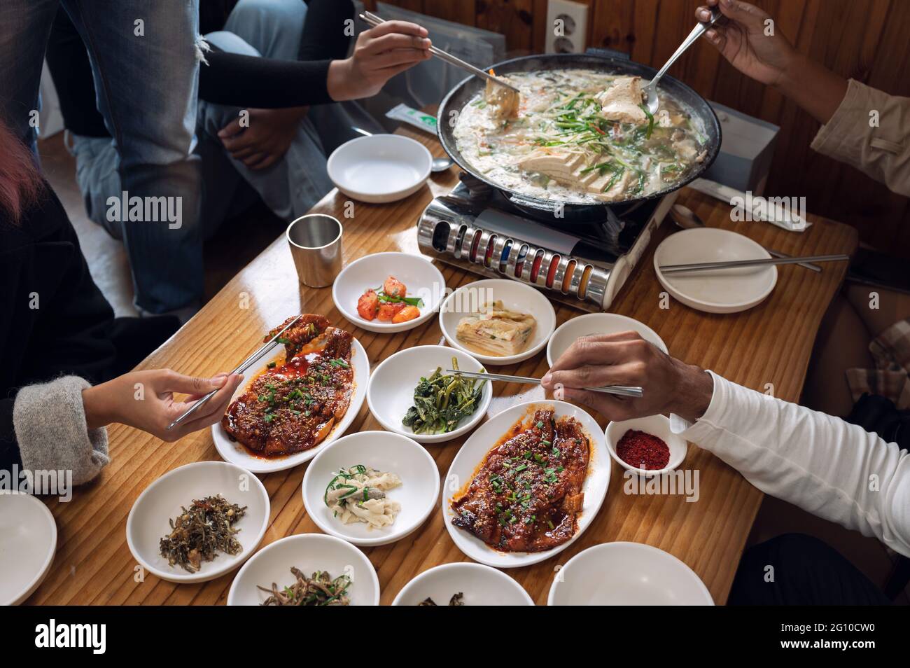 Hands with chopsticks clamping korean food and boiled tofu soup on ...