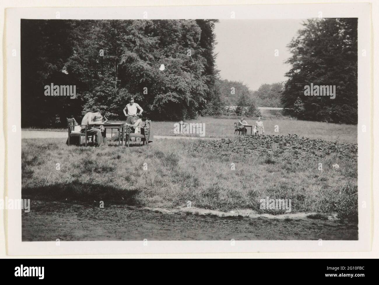 Group of German soldiers at a table. Two tables on a lawn surrounded by ...