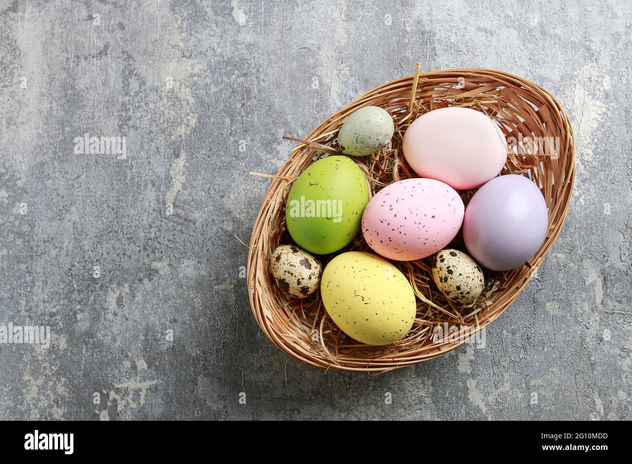 Basket of colorful Easter eggs on grey, stone background. Festive decor ...