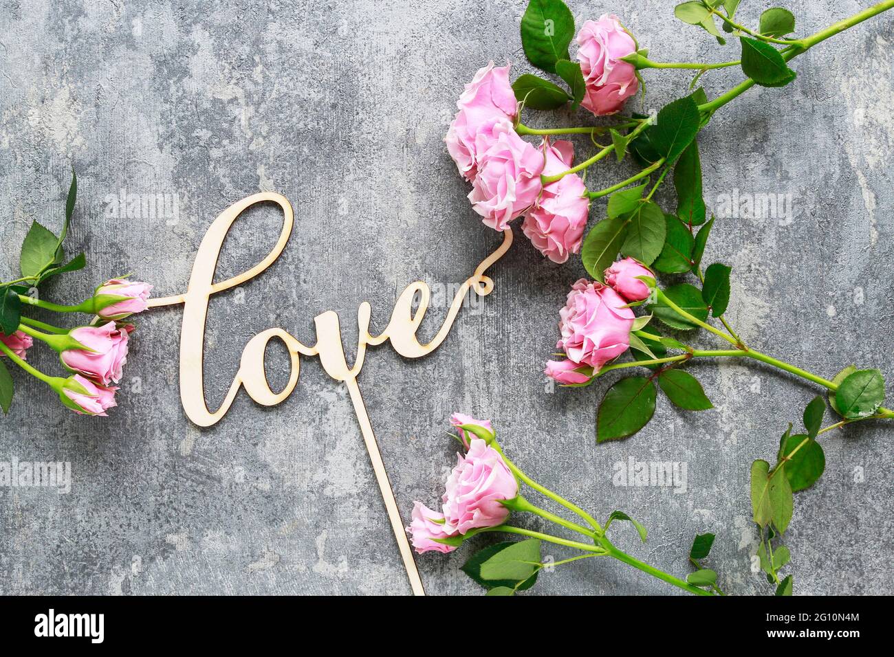 Handwritten love word and pink roses on grey stone background. Graphic ...