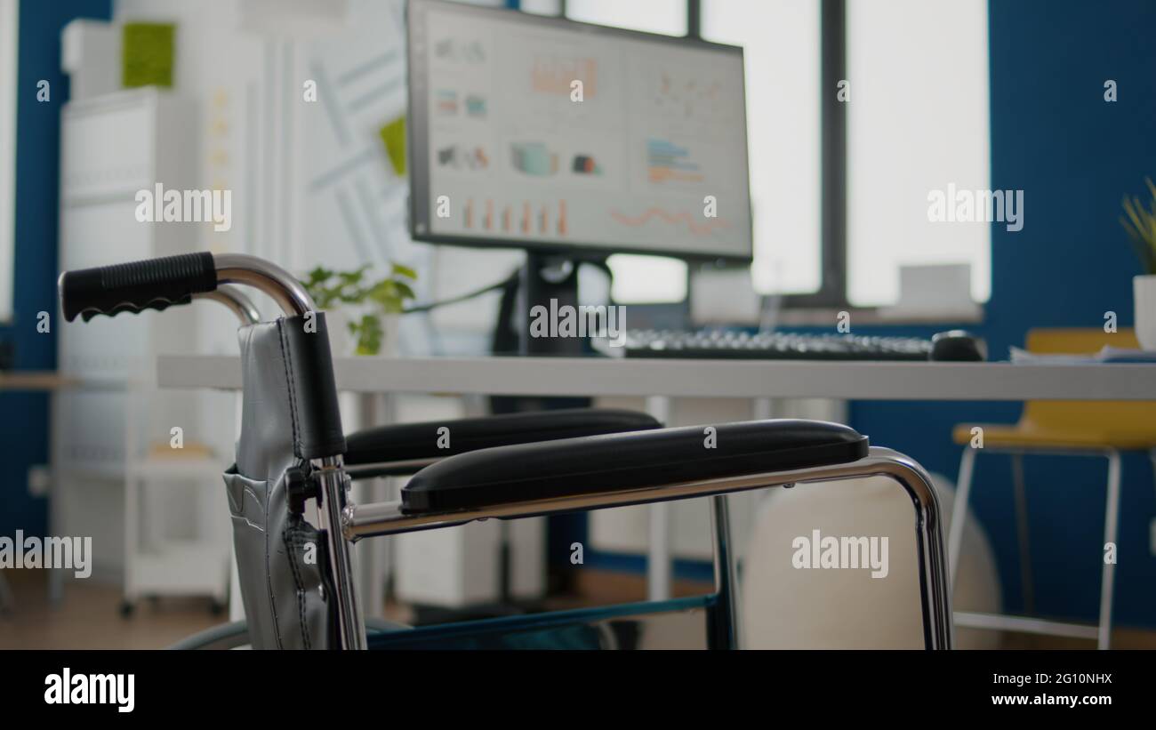 Interior of cozy light company room with wheelchair parked near desk ...