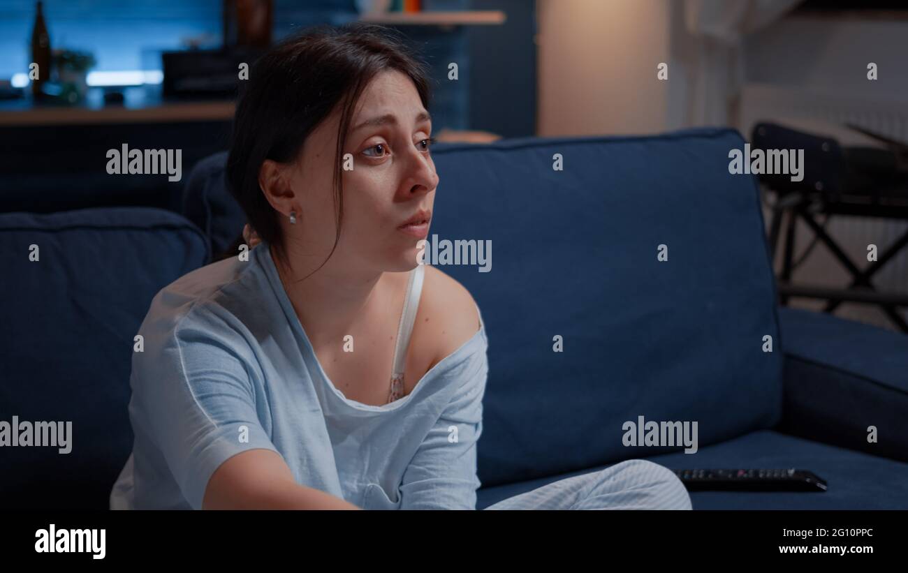 Sensitive woman watching drama movie on tv crying sitting on sofa ...