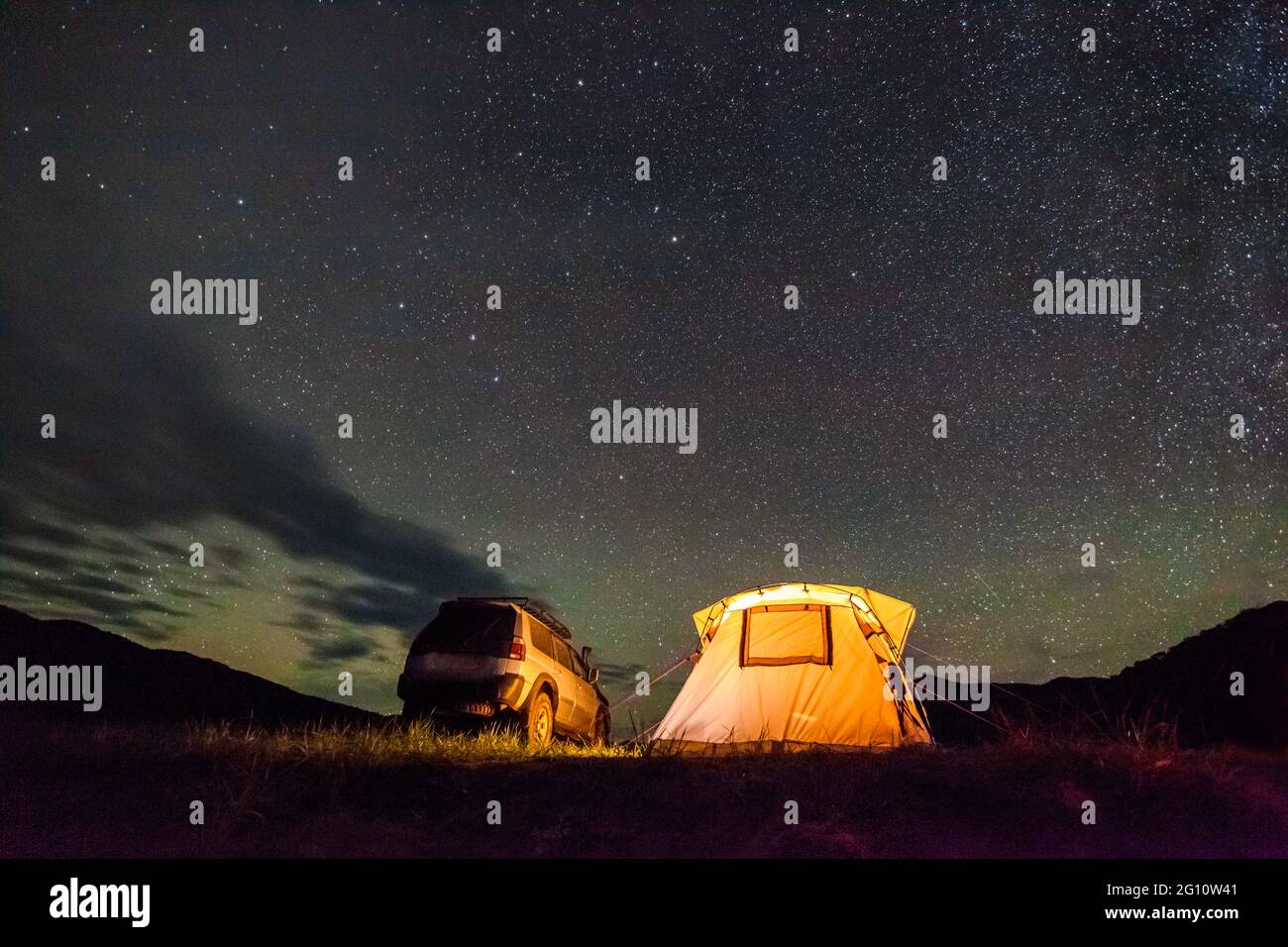 Tourist camping at sea coast at night under cloudy sky. Some noise from ...