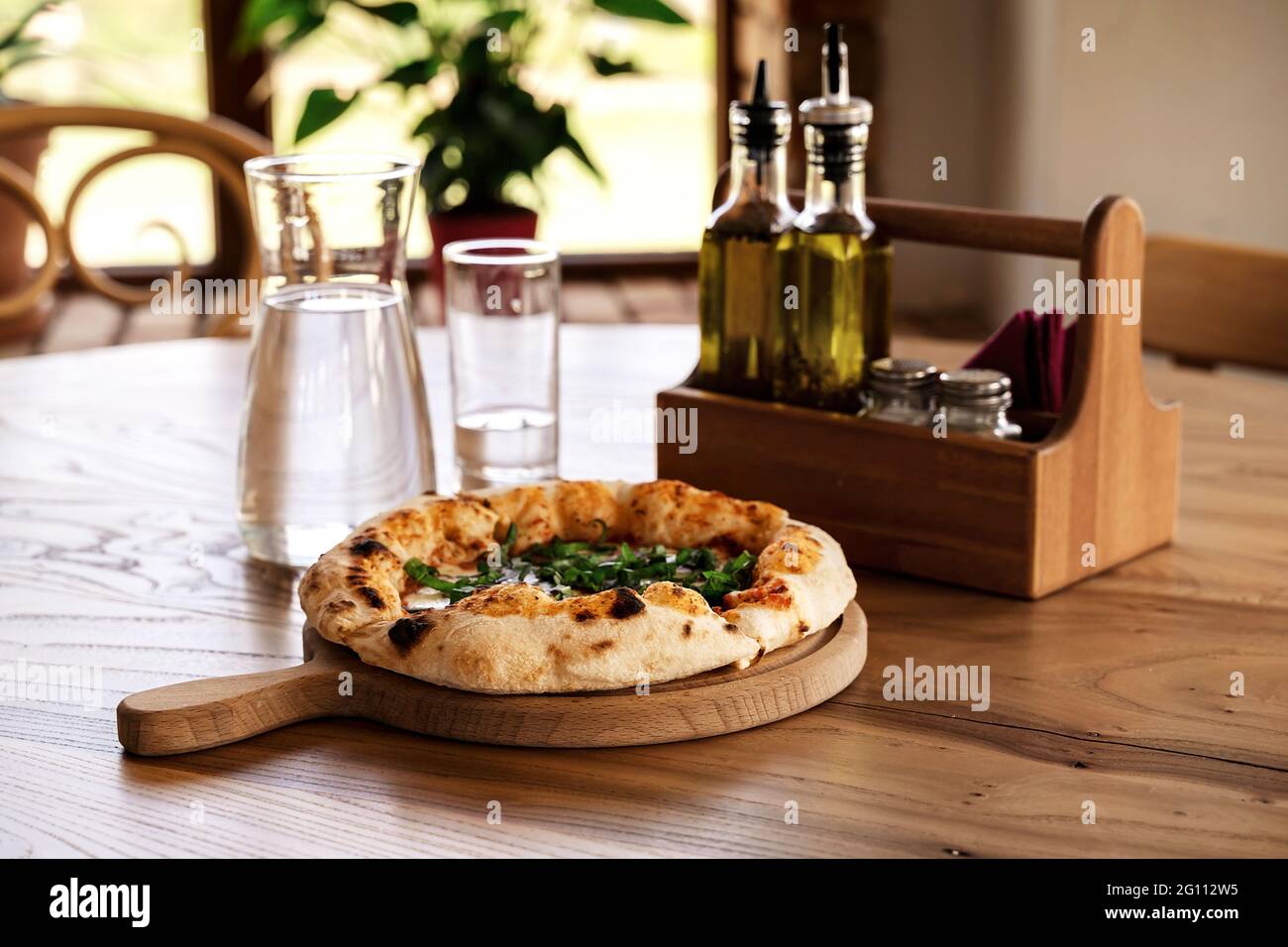 Pizza and water in glass jug on wooden table in vintage style. Italian ...