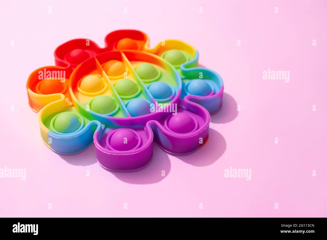 Rainbow pop it fidget toy on light pink background with copy space ...