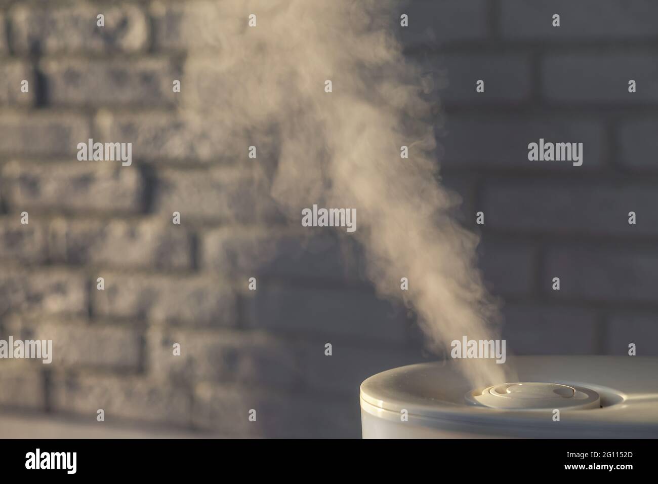 Humidifier spreading steam with white brick wall background. Loft style ...