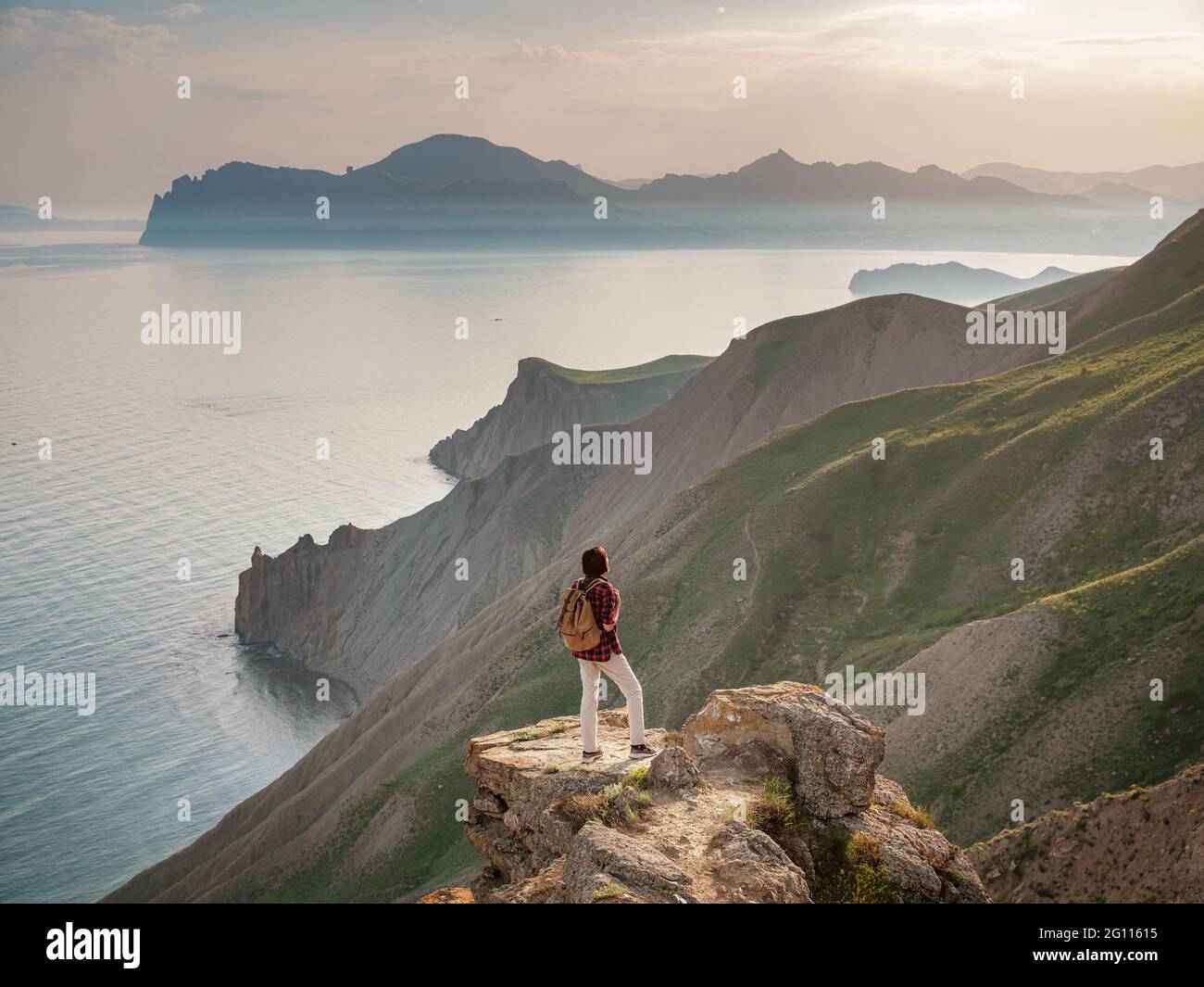 A young Asian woman with a backpack hiking in the summer. Mountain and ...