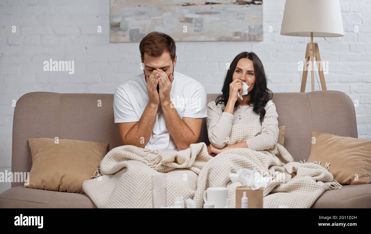 sick couple sneezing and coughing in living room Stock Photo - Alamy