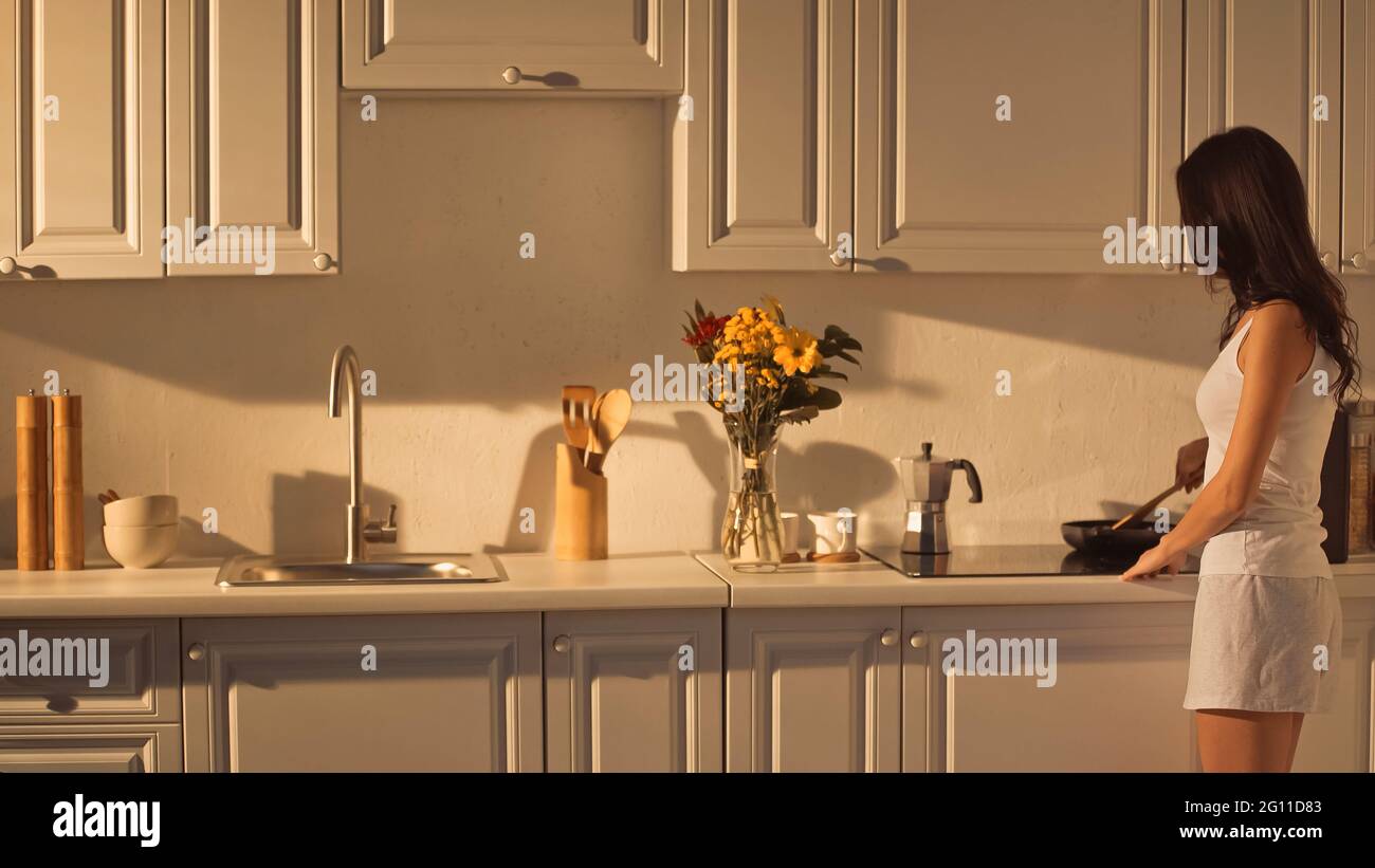 brunette young woman in pajamas cooking in modern kitchen Stock Photo ...