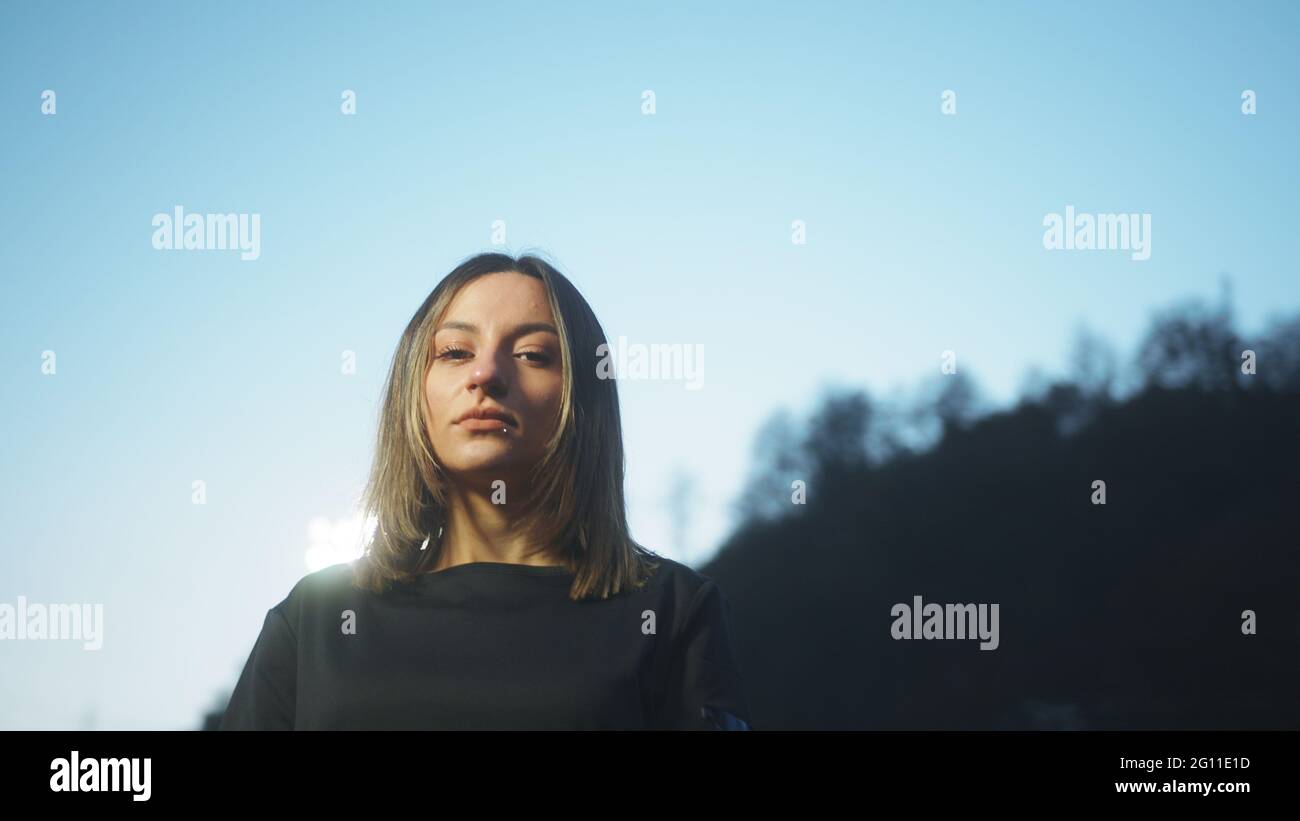 Portrait of young beautiful woman on blue sky and mountain background ...