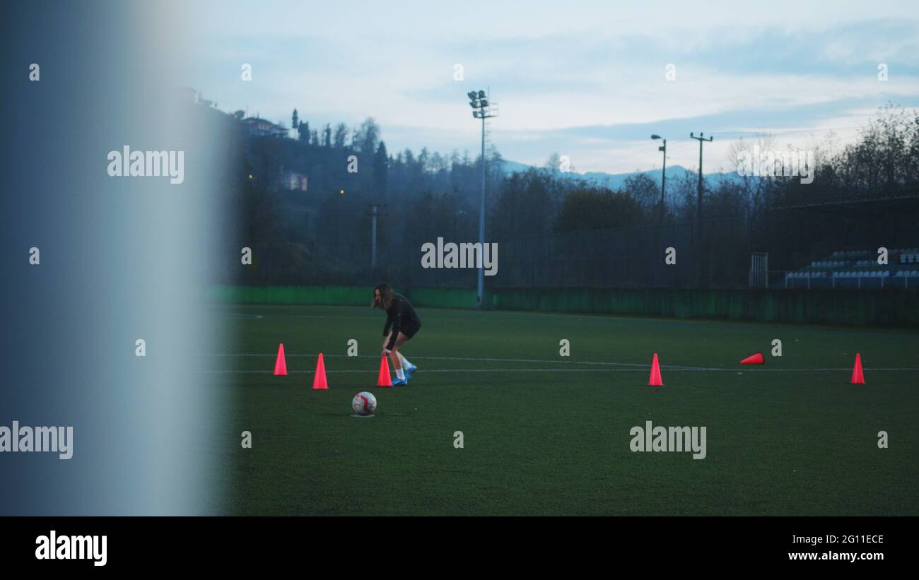 Young woman soccer player placing cones before kick the ball on the ...