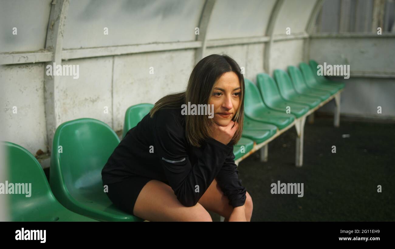 Reserve woman soccer player sitting on the bench, watching the game ...