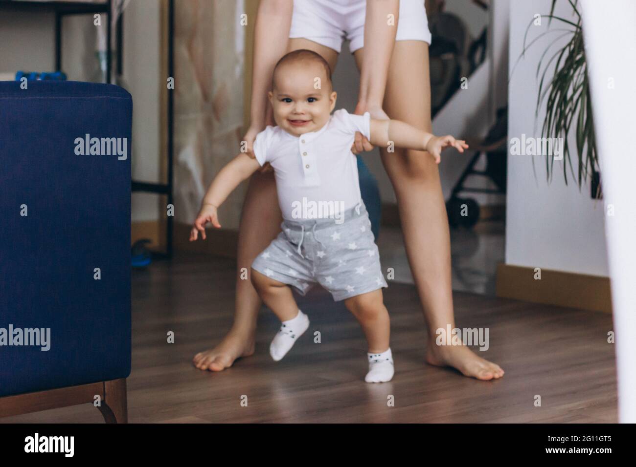 First steps of baby boy. Little child learning how to walk. Mother ...