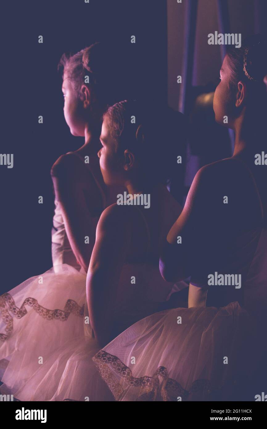 Side view of three little dancer watching a show from the backstage ...