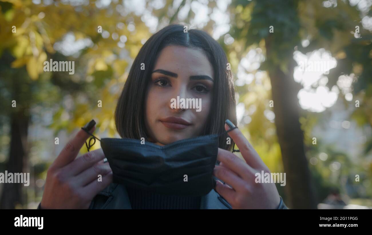 Young woman on the street during pandemic period and she is taking off ...