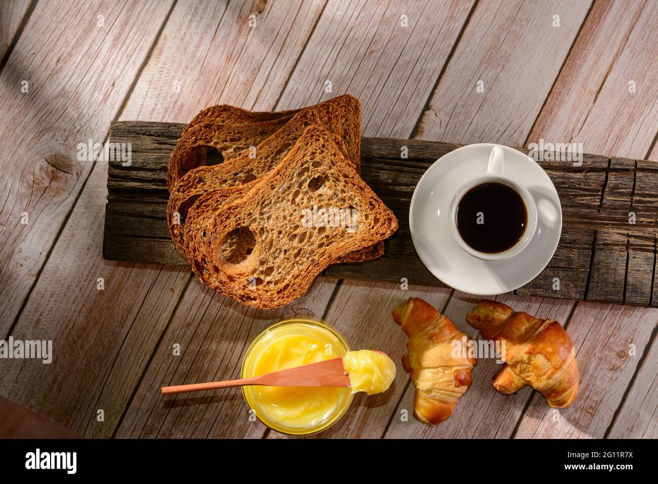 Ghee butter in glass jar with wooden spatula and sliced bread on wooden ...