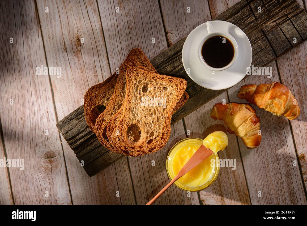 Ghee butter in glass jar with wooden spatula and sliced bread on wooden ...