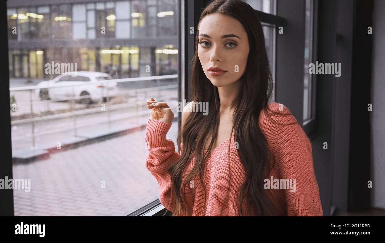 serious young adult woman standing near window in modern loft Stock ...
