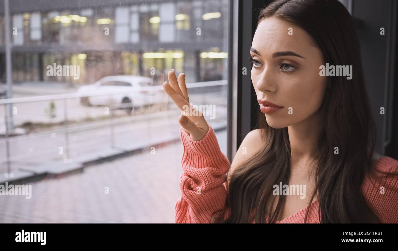sad young adult woman standing near window in modern loft Stock Photo ...