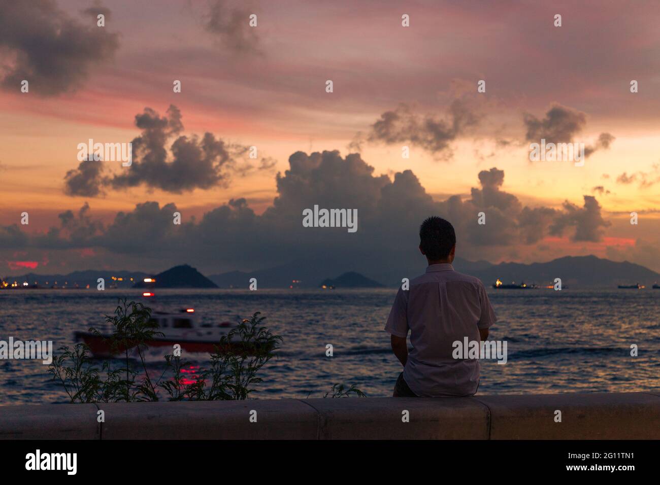 lonely young man enjoy sunset over Victoria Harbour at West Kowloon ...