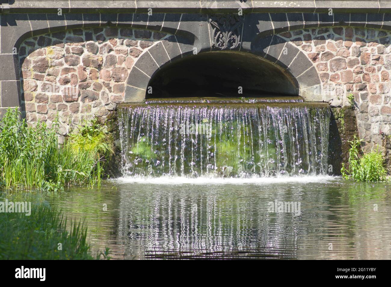 Small waterfall flows from a stone wall in the center of Arnhem in The ...