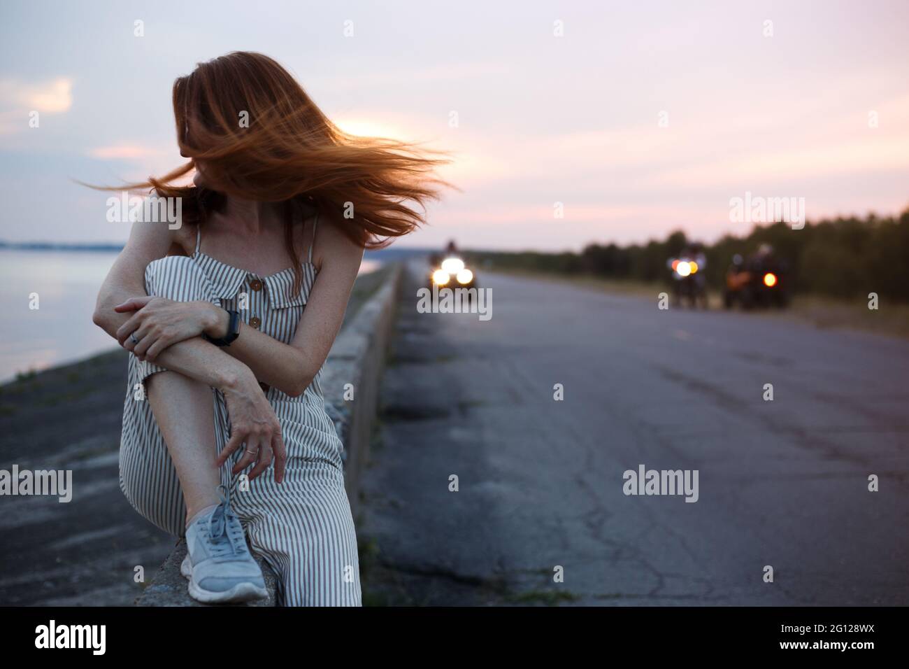happy girl sitting on the parapet. road in the background. atmosphere ...