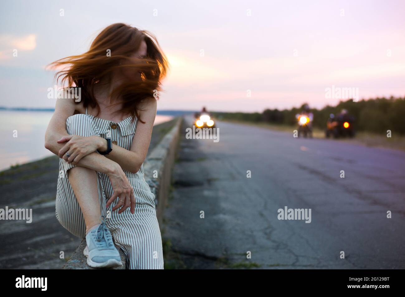 happy girl sitting on the parapet. road in the background. atmosphere ...