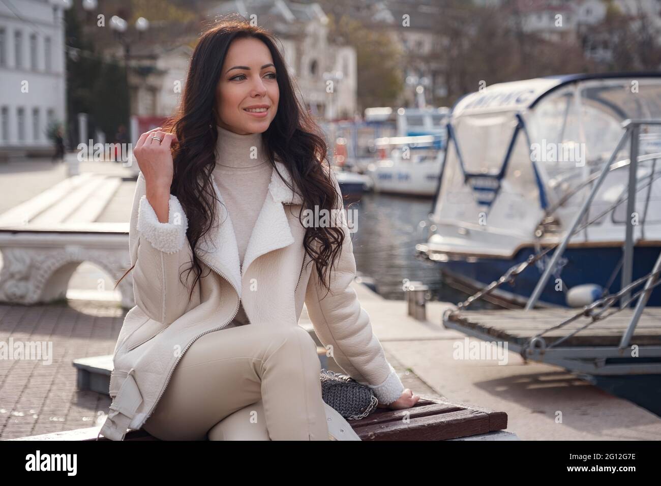 A carefree Caucasian woman in beige clothing enjoying the view of the sea on a warm, windy day ...