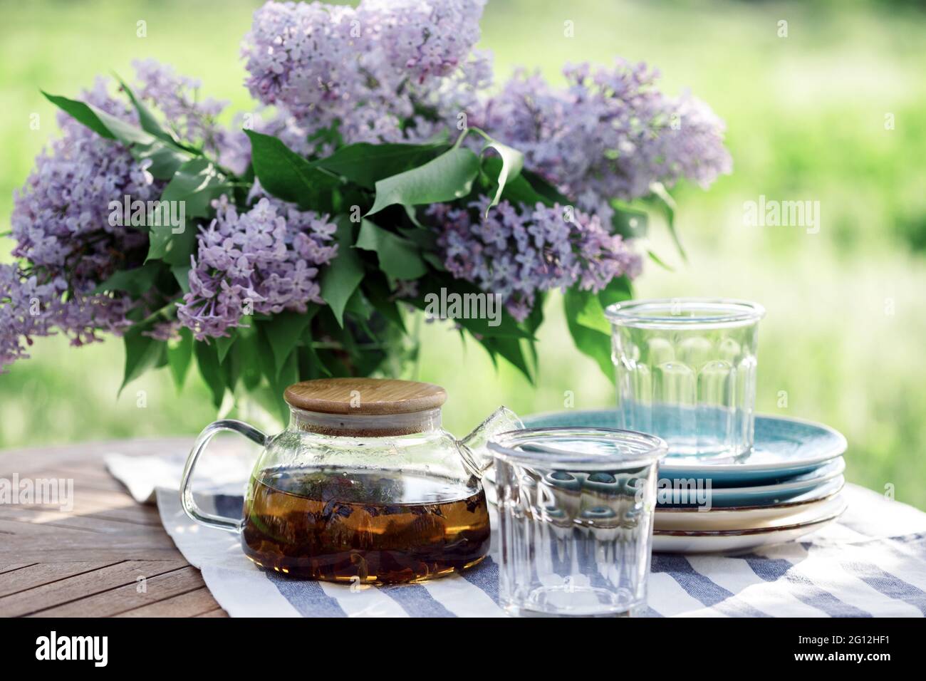 tea party in the garden. bouquet of lilacs, tea and glasses on the ...