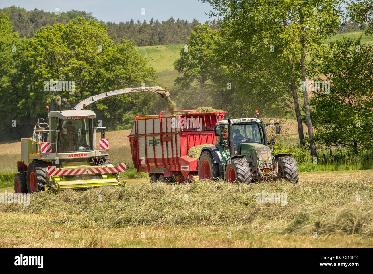 Farmers with big agricultural machines make the hay, hay making with ...